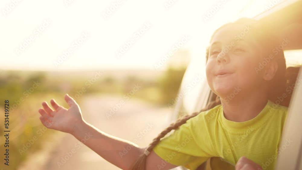 girl child travel in car. happy kid waving from the car out the window ...