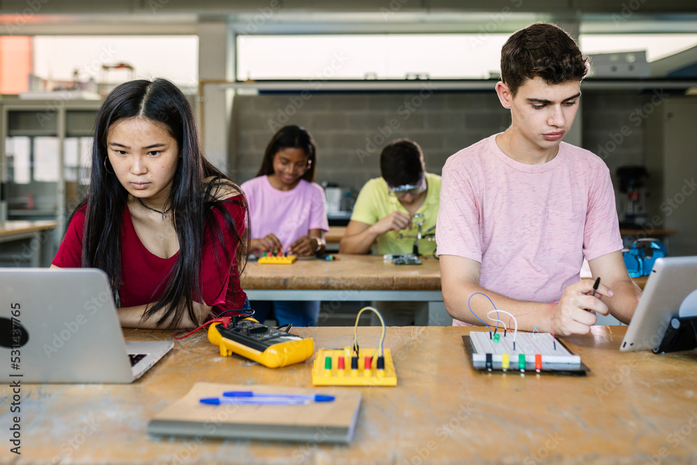 Multiracial group of high school students programming electronic ...