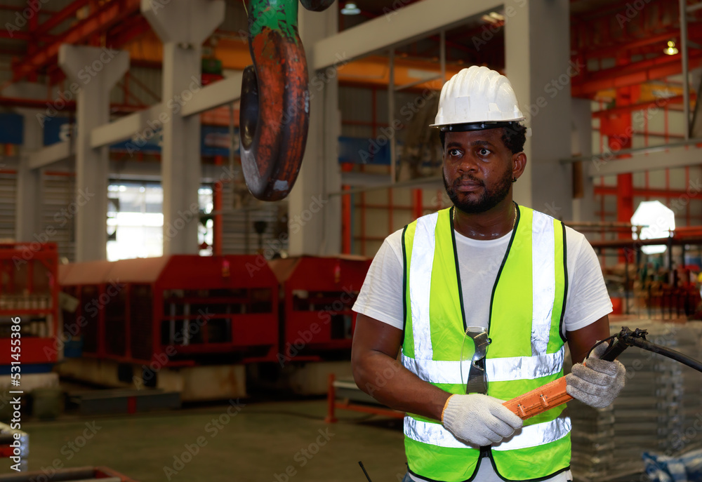 An African American male technician operates a machine inside a factory ...