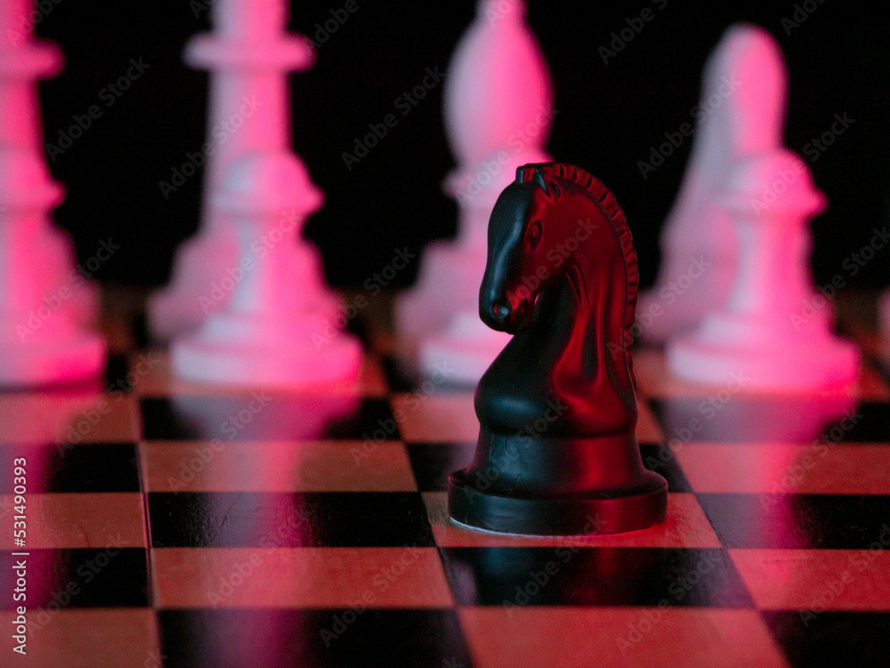 Black horse chess piece on a chessboard. Chess match. Bright red light ...