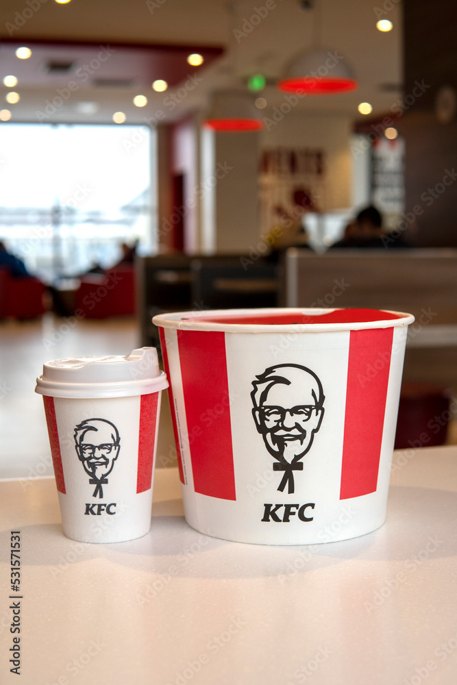KFC basket with fried spicy chicken and KFC cup of tea stand on the ...