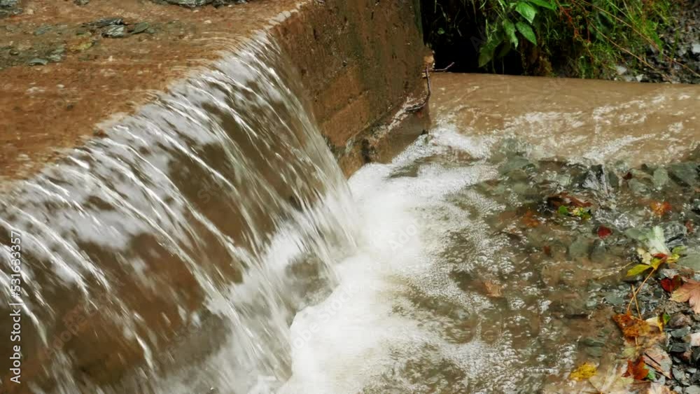 4K. Nature river waterfall that overflows over a forest road after a ...