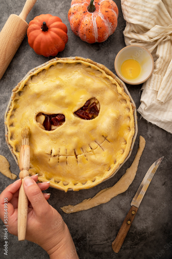 Cooking halloween apple pie, pumpkin face cutted in raw dough. Autumn ...
