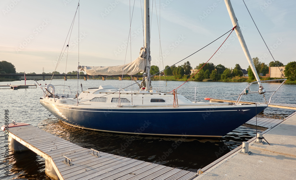 Sloop rigged sailboat (for rent and sale) moored to a pier in a yacht ...