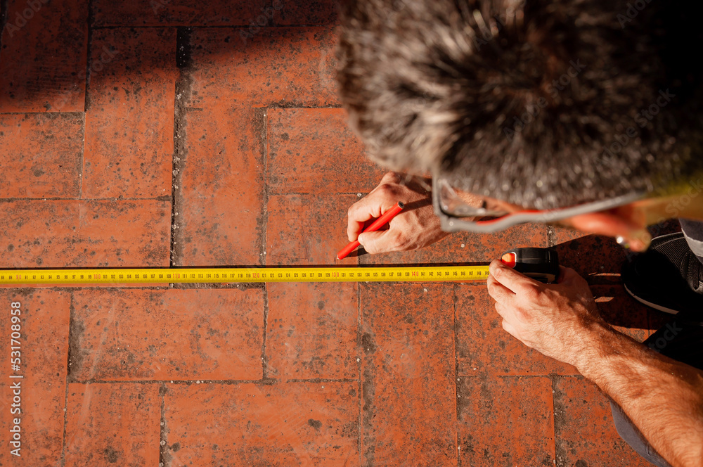 Working man using a tape measure and making distance marks on the ...