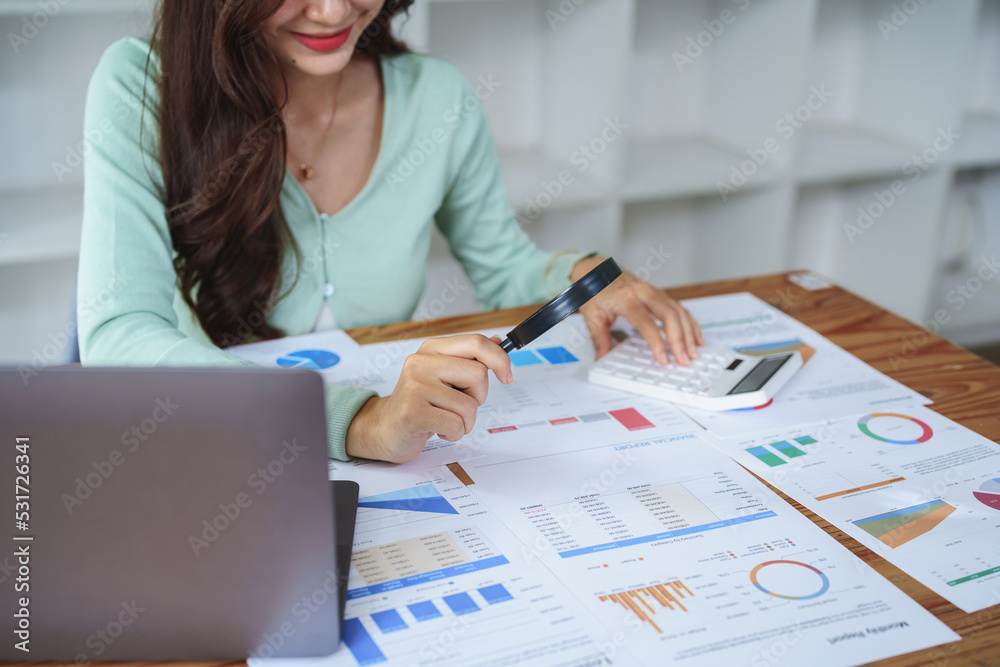 accountant holding a magnifying glass and using a calculator to check ...