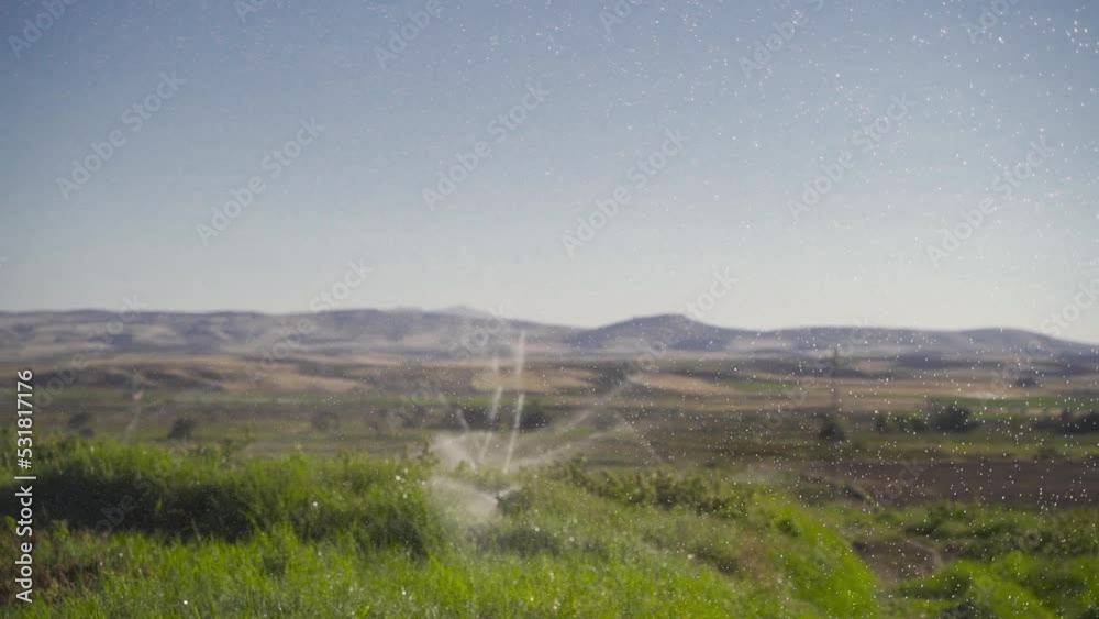 Irrigation system with sprinklers in field in slow motion. They rotate ...