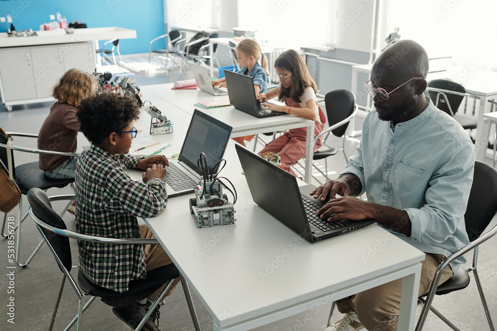 Group of creative intercultural schoolkids and their teacher using ...