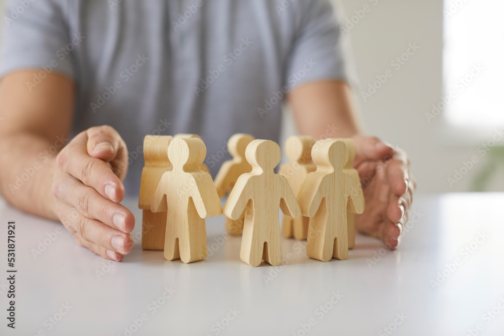 Man guarding small wooden human figures. Close up of male hands and ...