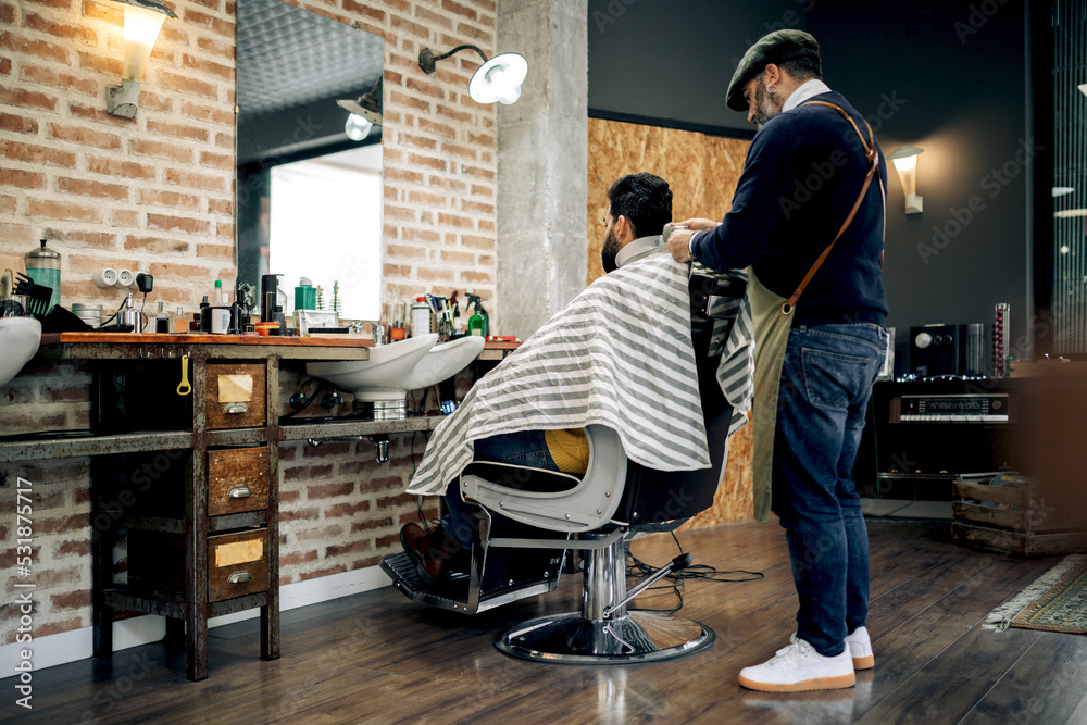 Crop barber brushing hair of client in salon Stock Photo | Adobe Stock