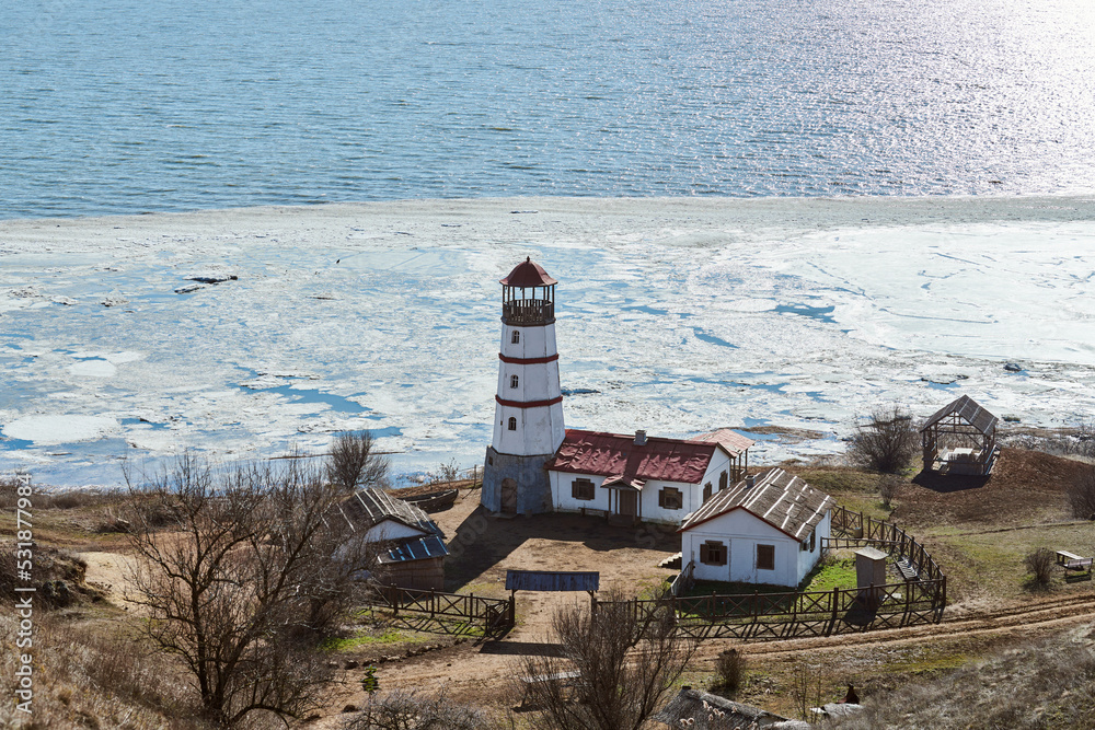 Beautiful white red lighthouse with farm utility houses in Merzhanovo ...