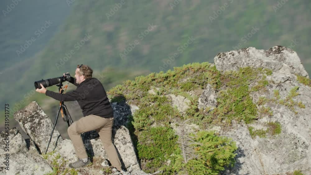 Photographer attaches hood to telephoto lens on camera on mountain ...