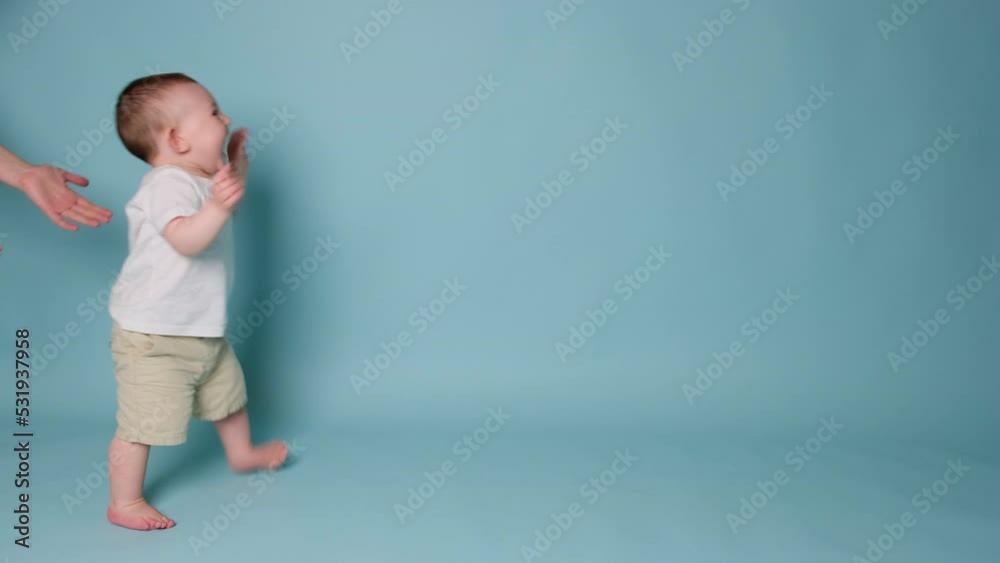 Happy toddler baby learns to walk and takes his first steps. Child boy ...