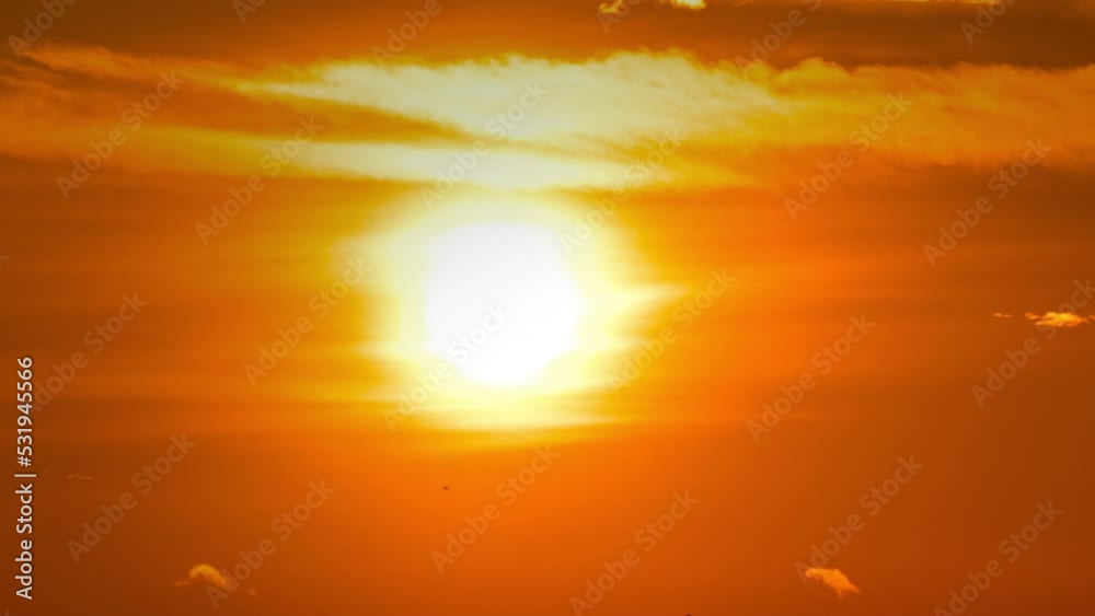 Time lapse bright orange sunset sun sets behind the clouds. The end of ...