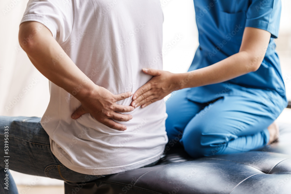 Physical therapist is examining the injured arm, waist and neck muscles ...
