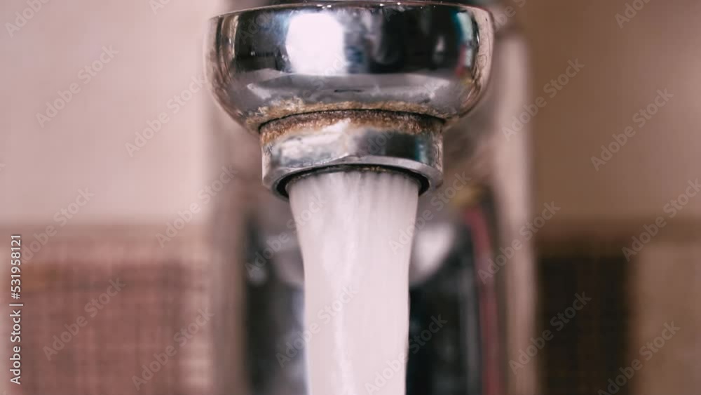 Close-up of water flowing from the faucet in the bathroom. The flow of ...
