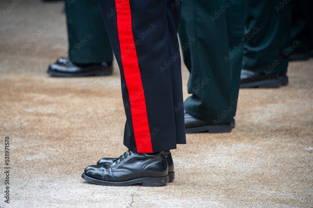 A group of men and women standing at attention in black uniform suits ...