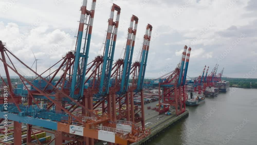 Fly along row of big gantry cranes on waterfront in harbour. Export and ...