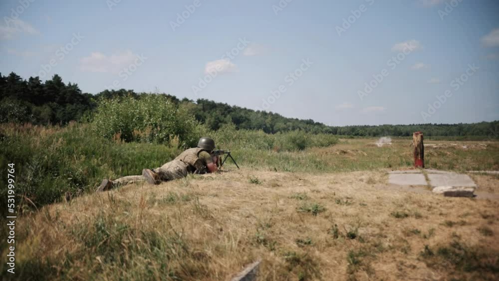 Military man in green uniform vest unloading gun with machine gun in ...