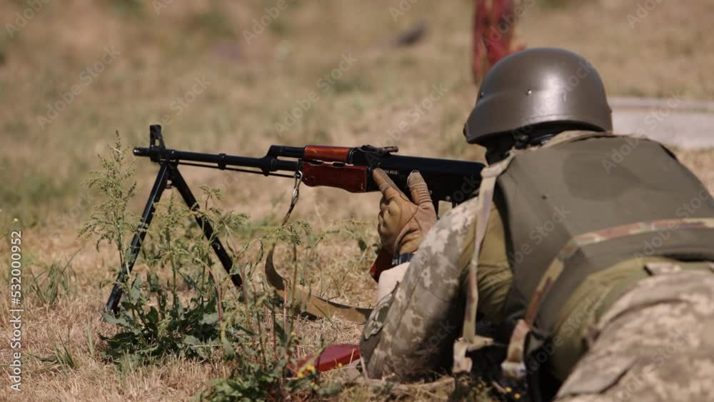 Armed military man unloading machine gun while lying with gun, soldier ...