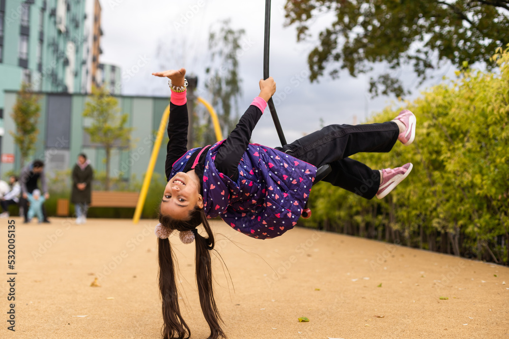 Little girl rides on Flying Fox play equipment. Child girl is smiling ...