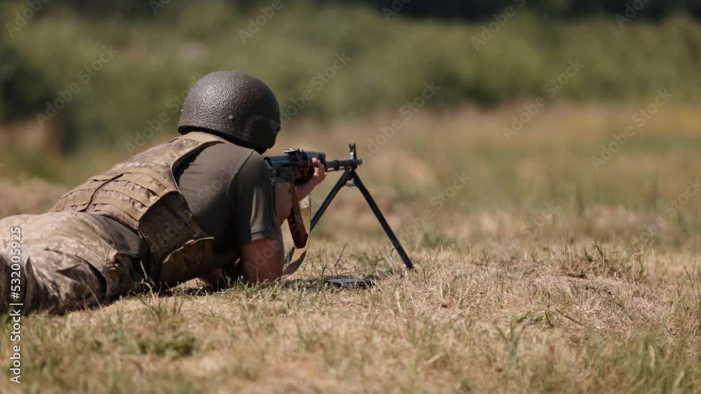 Armed military man unloading machine gun while lying with gun, soldier ...