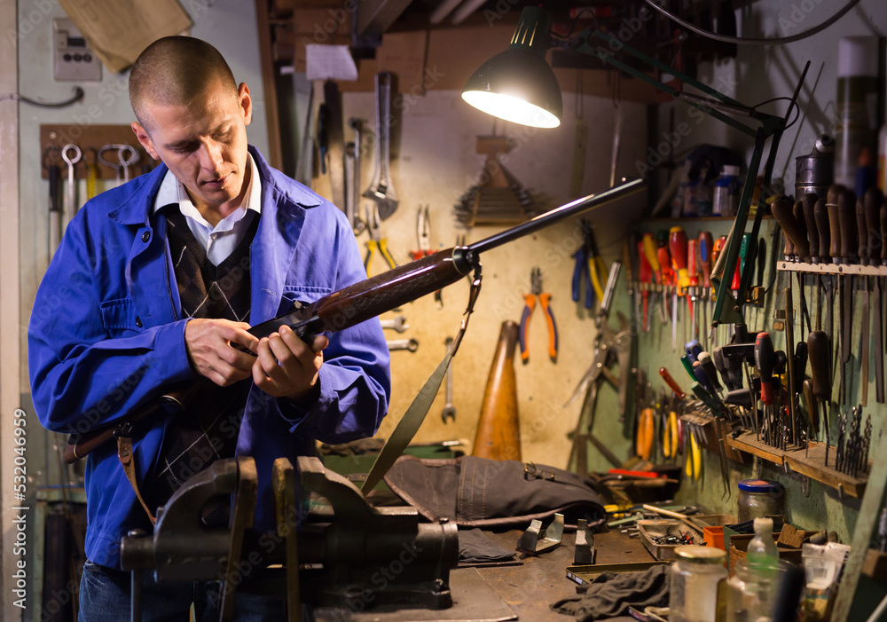 Gunsmith examines an automatic rifle before being repaired in a weapons ...