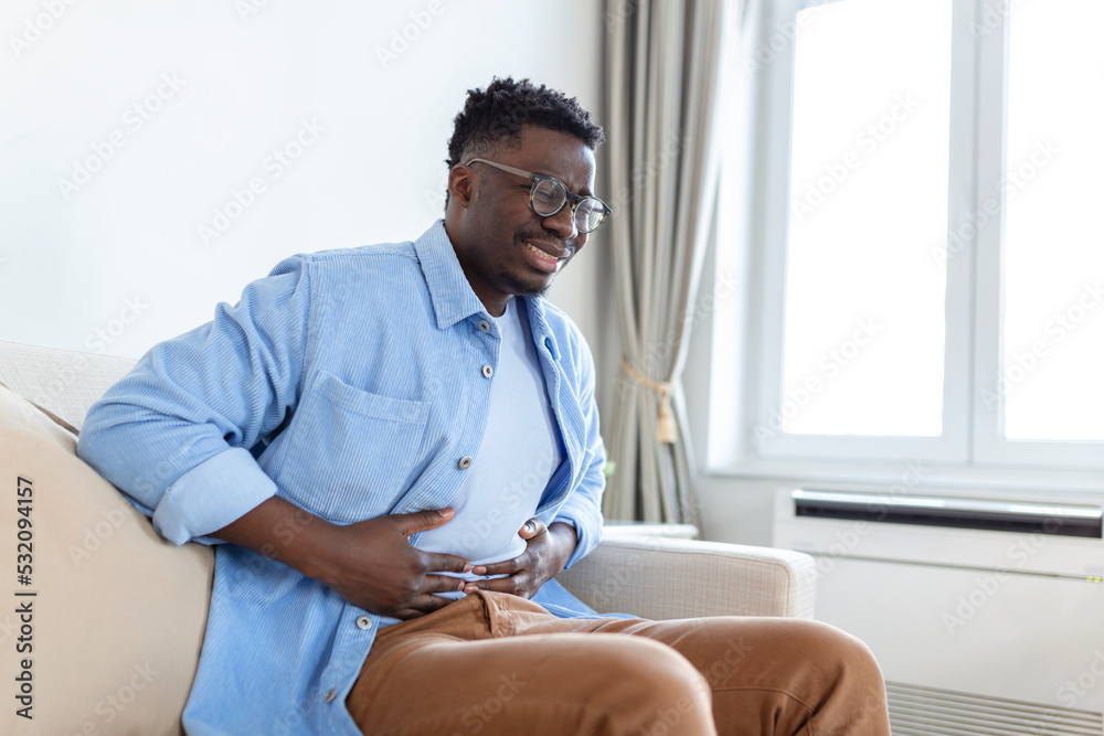 Young African man holding his stomach in pain, Man with reflux disease ...