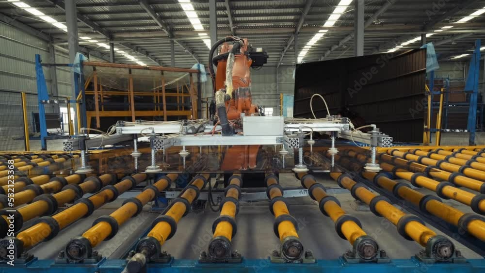 Robotic arms automatically take flat glass from a conveyor line and ...