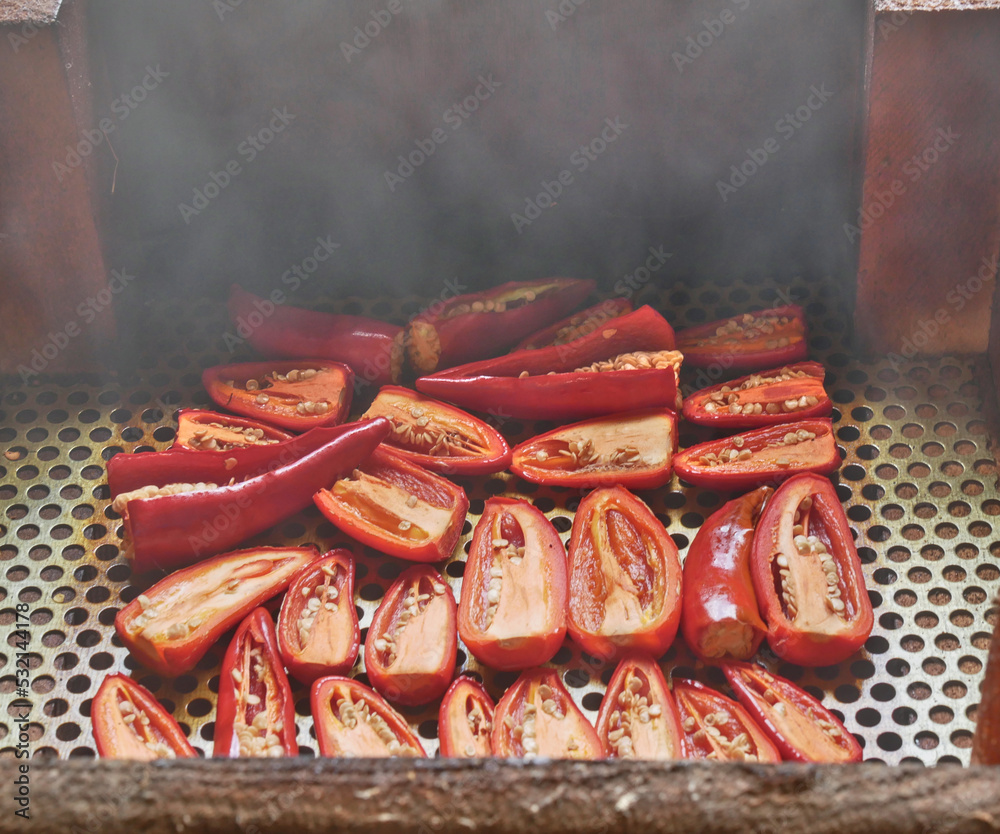 Cold smoking of jalapeno peppers, cut in half and placed on a grid of a ...