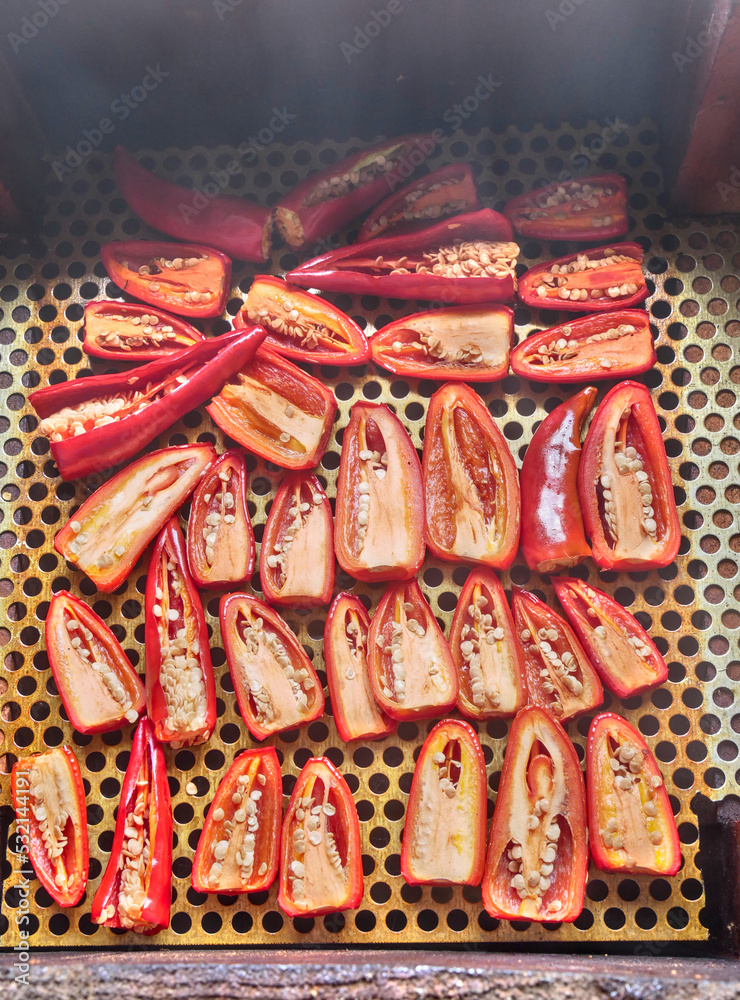 Cold smoking of jalapeno peppers, cut in half and placed on a grid of a ...