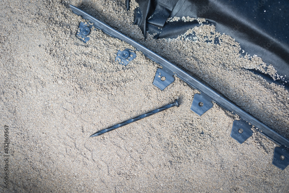 Anchoring spikes next to black plastic landscape edging with level ...