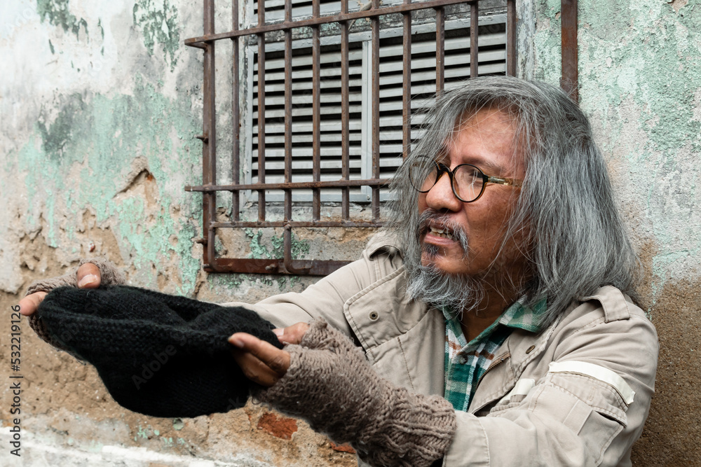 An old homeless Asian man is reaching out to a passerby asking for ...