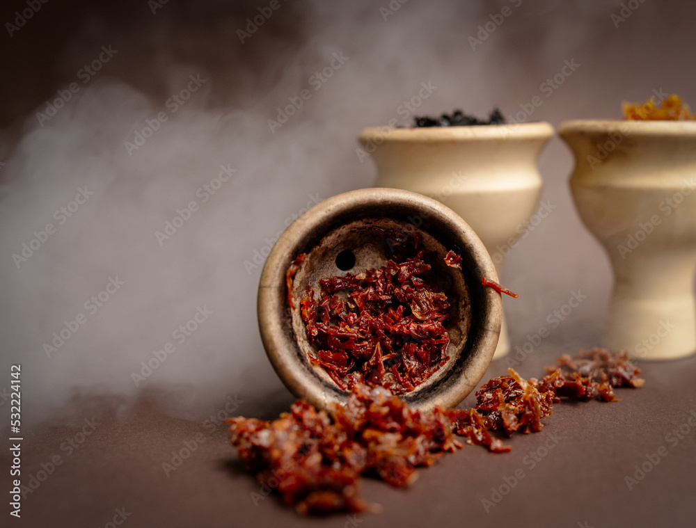 Three hookah bowls with aromatic tobacco with smoke on a brown table ...