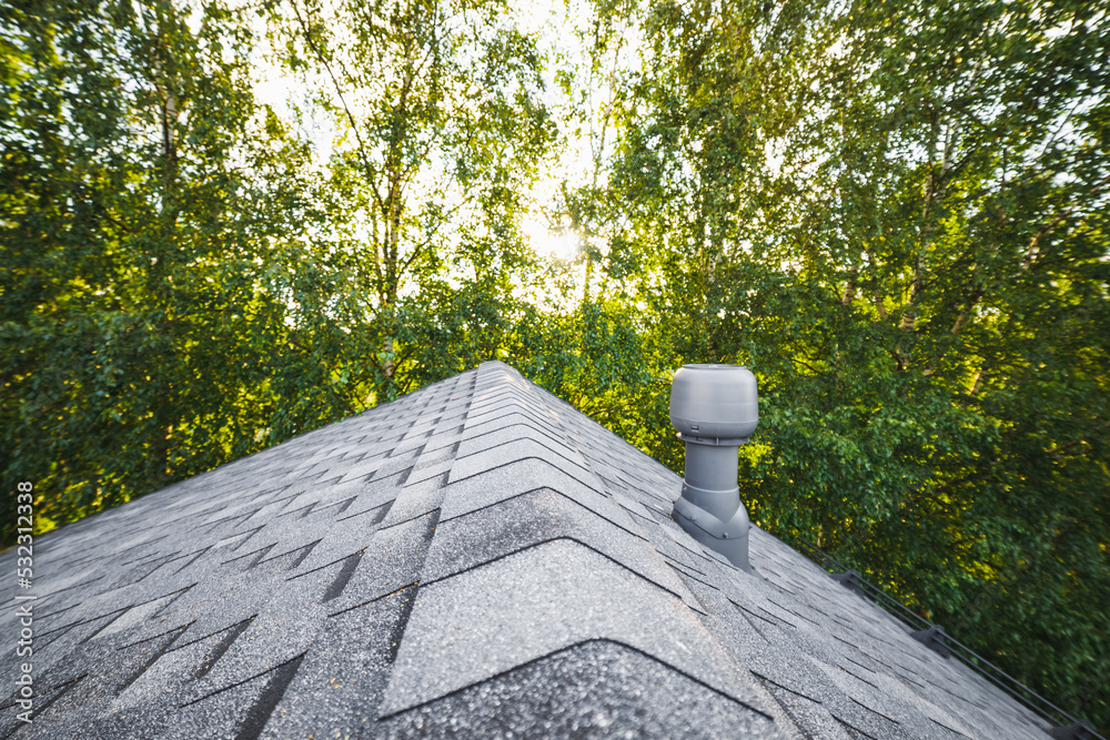 renovated roof ridge with shingles roof-tiles of a house and ...