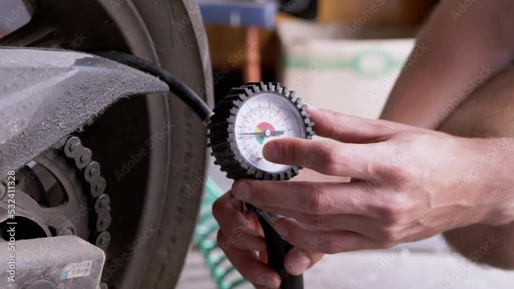 Wideo Stock: Male Checks the Air Pressure in a Motorcycle Tire with a ...