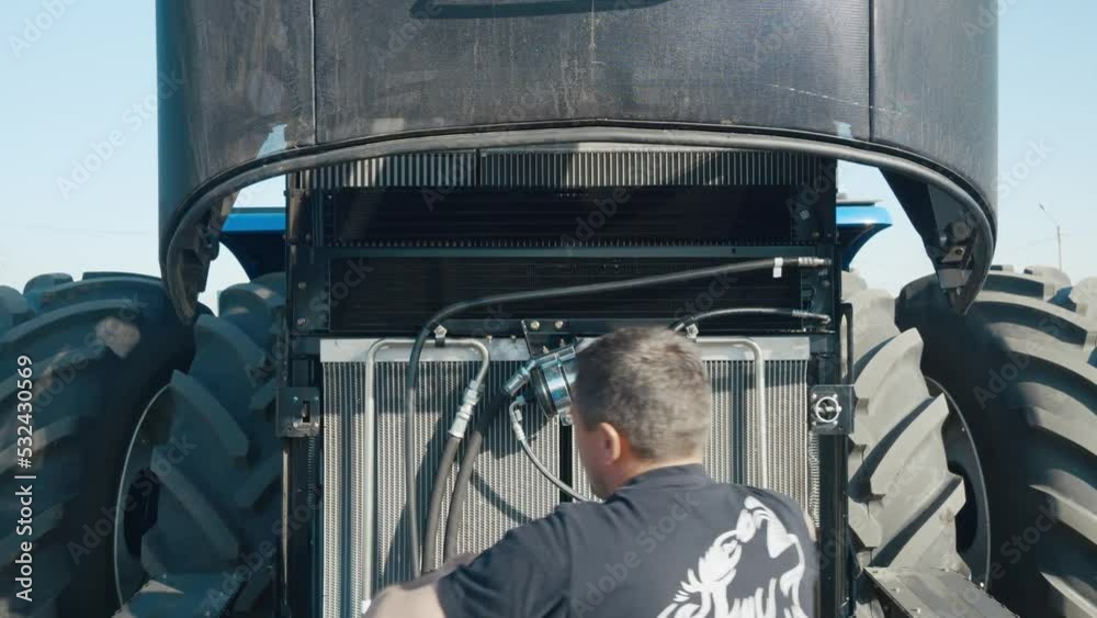 The driver closes the tractor radiator grille. Tractor is in the middle ...