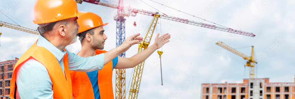 Older construction supervisor with younger worker helper at ...