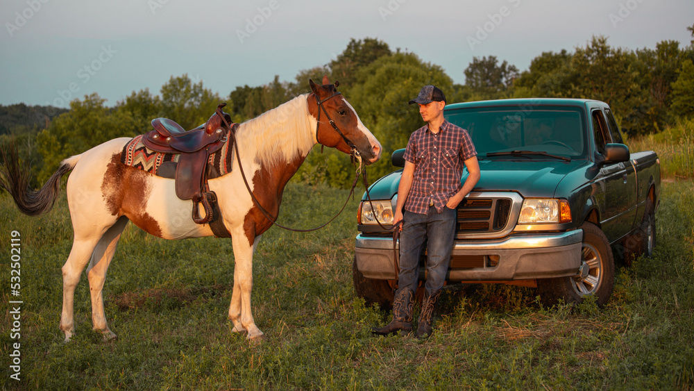 A cowboy on a ranch near a pickup truck. Western horse on the field at ...