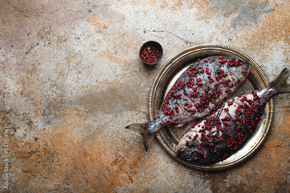 Two raw fishes dorado seasoned in pink peppercorn ready to be cooked ...