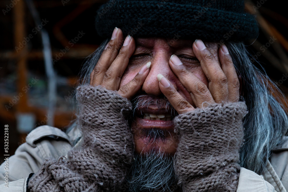 Close-up of the face of a dirty-dressed, long-haired, homeless old man ...