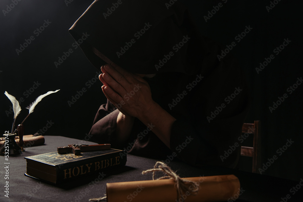 priest obscuring face with praying hands near crucifix on holy bible ...