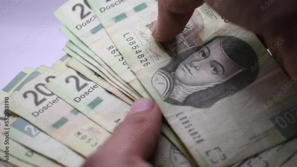 Plano detalle de una mano contando billetes de doscientos pesos ...