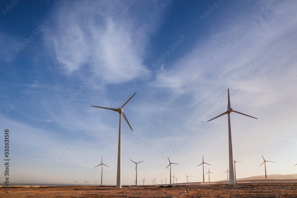 Renewable energy, wind turbines power plant at sunset, blue sky. Stock ...