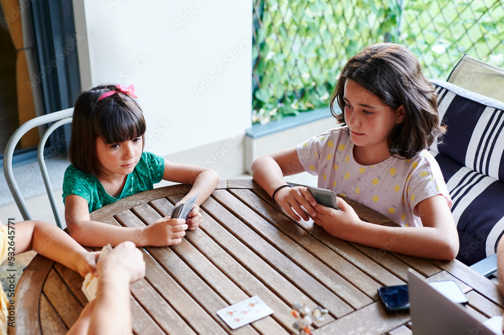 Girl playing cards with her siblings outside Stock Photo | Adobe Stock