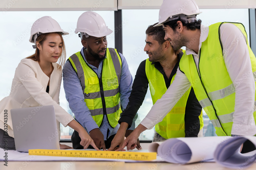 Team Engineers with draft plan of building on constructing site ...