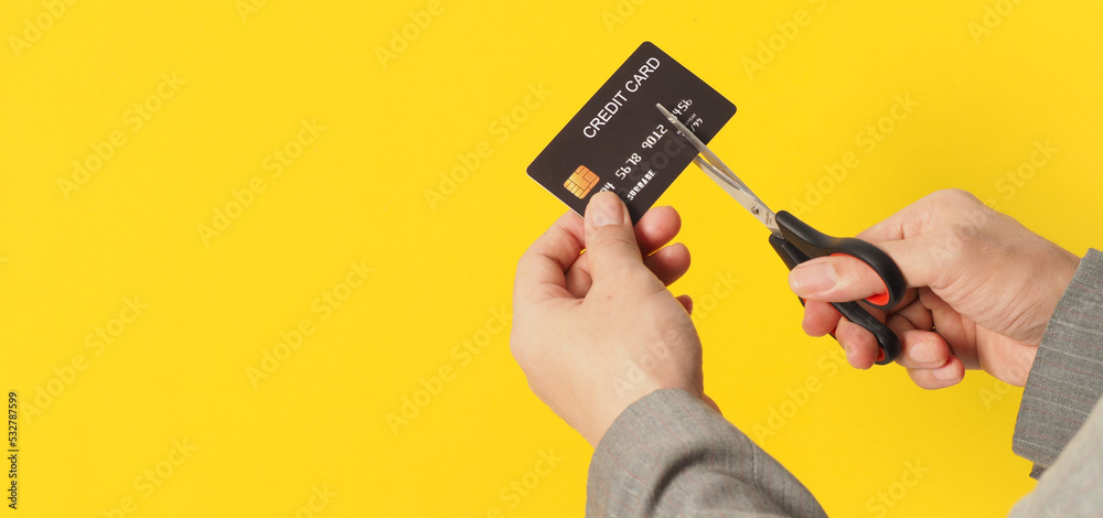 Hand is hold black credit card and scissors on yellow background. Man ...