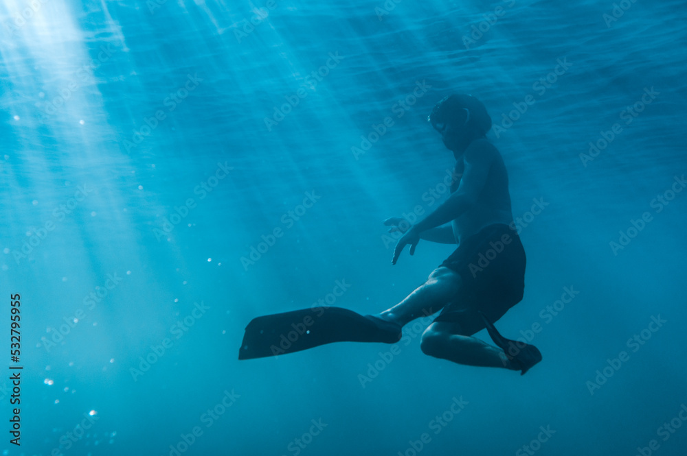 Man diver swimming under water in deep blue ocean wearing dive mask and ...