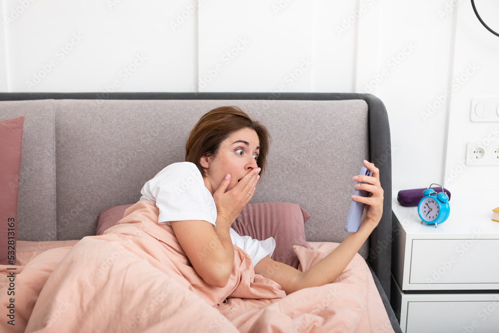 Young shocked woman waking up too late. Sleepy girl lying on the bed ...