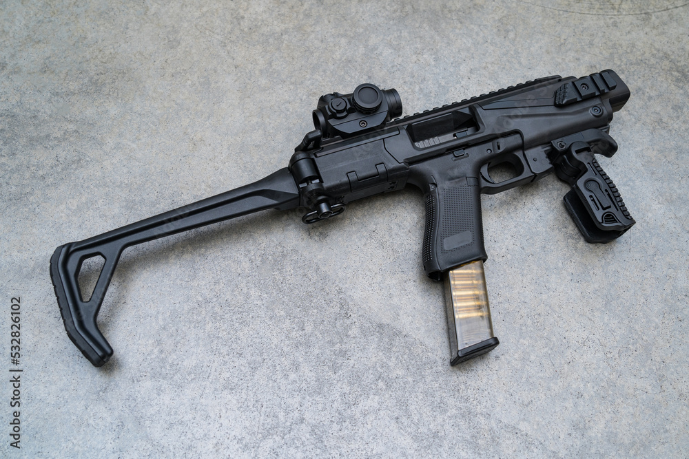 9mm pistol in a tactical conversion kit. Stock Photo | Adobe Stock